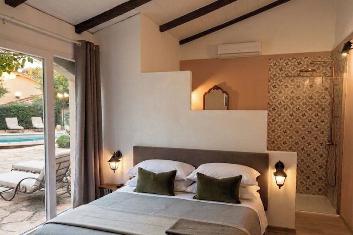 Quarto com cama, duas luzes na parede, janela e área de chuveiro.