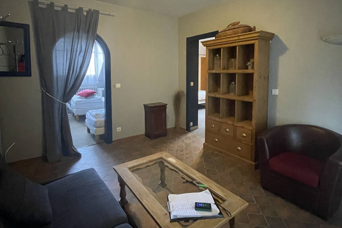 Uma sala de estar com sofá, mesa de centro de madeira, estante e uma cadeira vermelha.