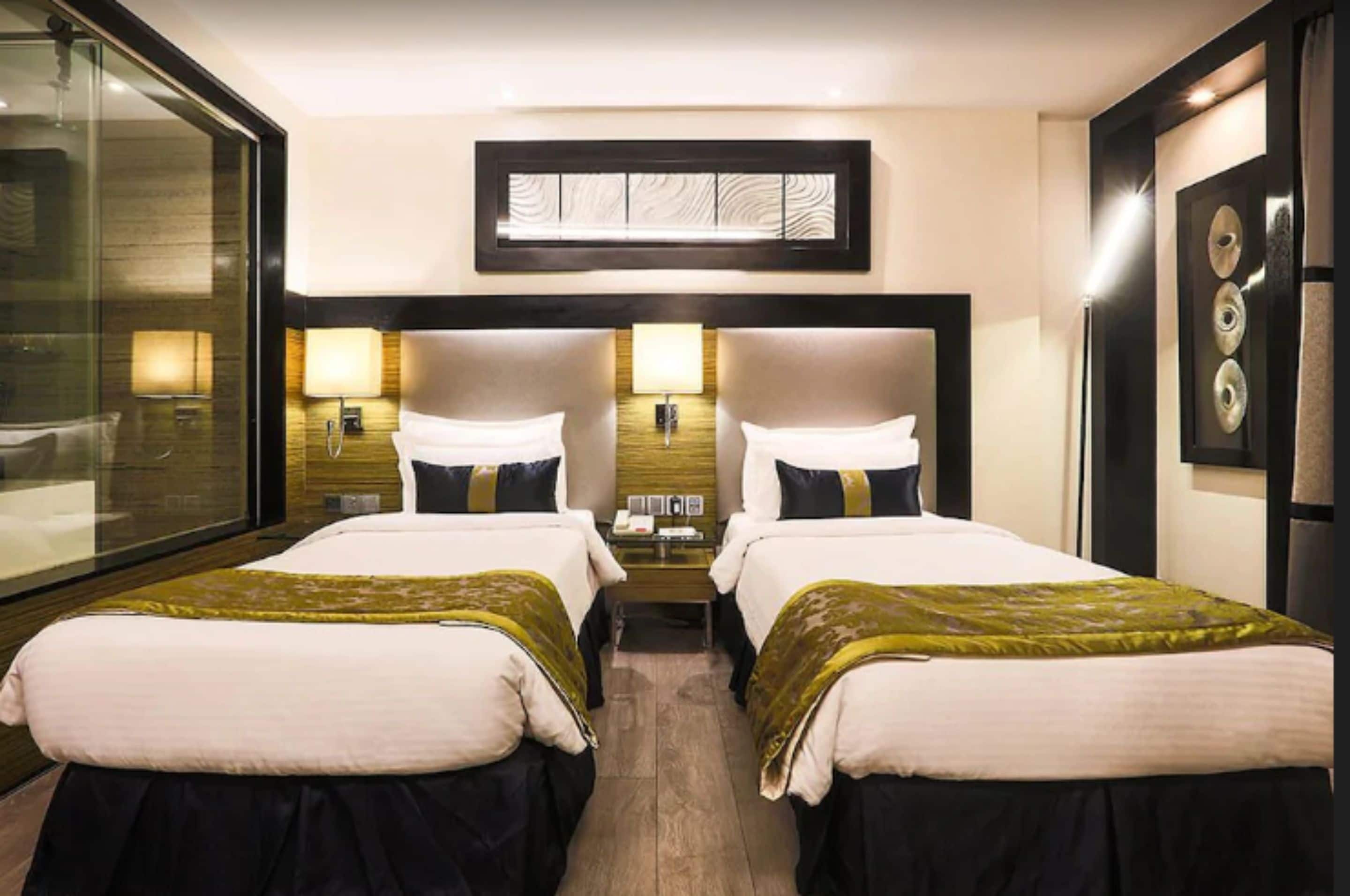 Quarto de hotel com duas camas, uma janela grande e design moderno.