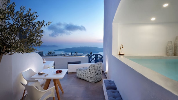 Uma área de estar moderna ao ar livre, com piscina, paredes brancas e vista para o mar.