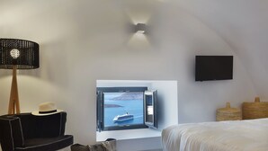 Quarto com uma janela grande, cama, televisão e uma cadeira.