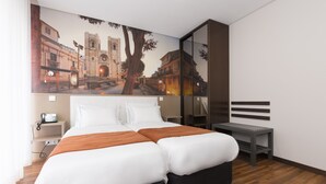 Quarto de hotel com uma cama grande, mesa de cabeceira com telefone, um banco e um mural com vista urbana na parede.