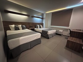 Quarto de hotel moderno com duas camas, uma mesa de escritório e uma janela grande.