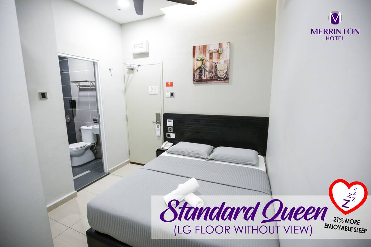 Quarto Standard Queen com piso LG, sem vista, chuveiro, vaso sanitário e cama com cabeceira e travesseiros.