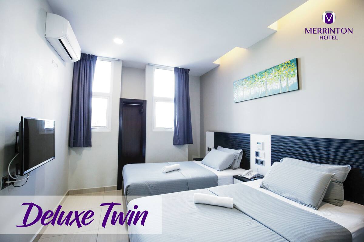 Quarto Deluxe Twin com duas camas, televisão, ar condicionado e um quadro na parede.