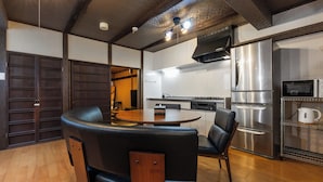 Cozinha moderna com mesa de jantar redonda, assentos de couro preto e eletrodomésticos de aço inoxidável.