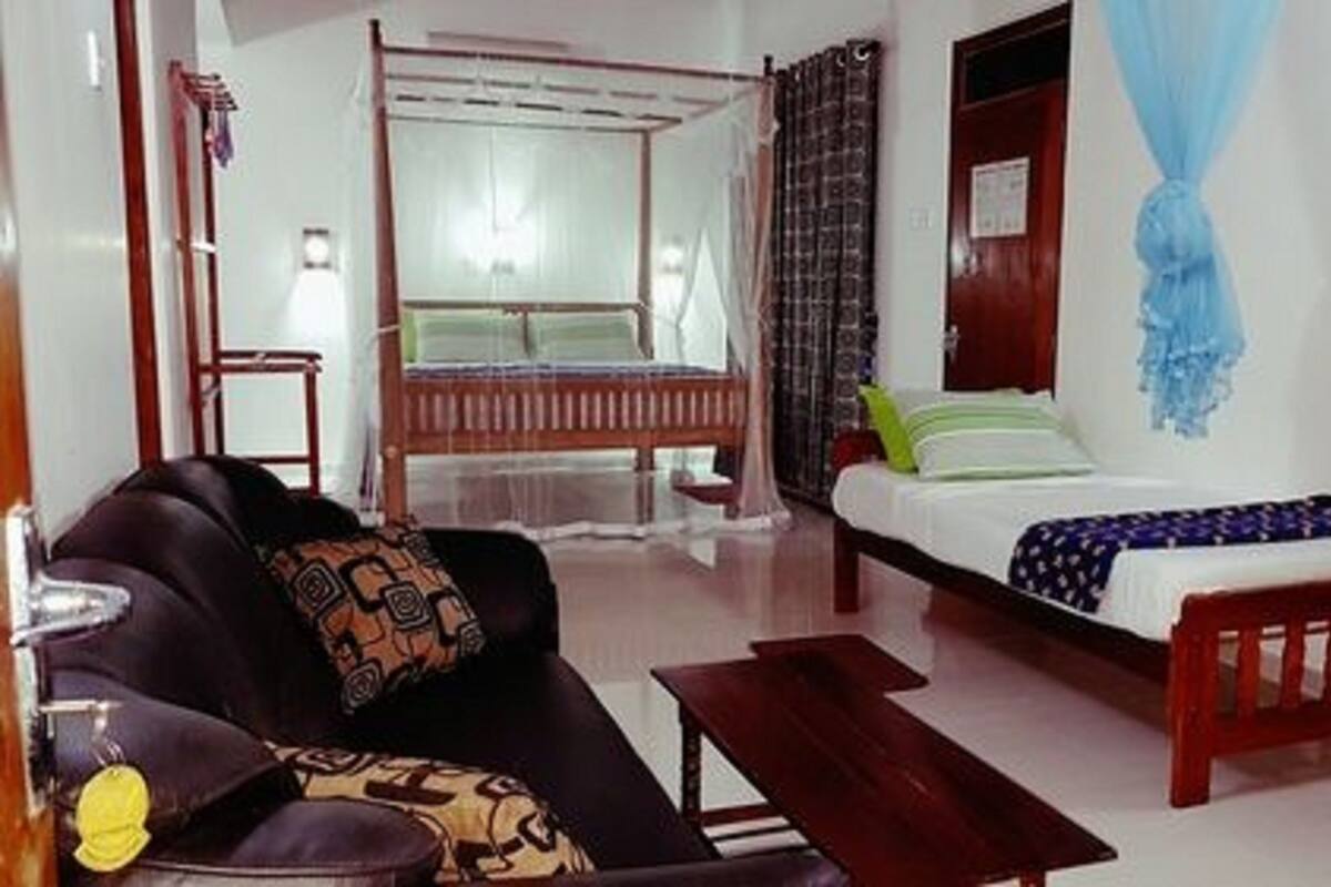 Um quarto com uma cama, um sofá, uma mesa de madeira e uma cadeira.