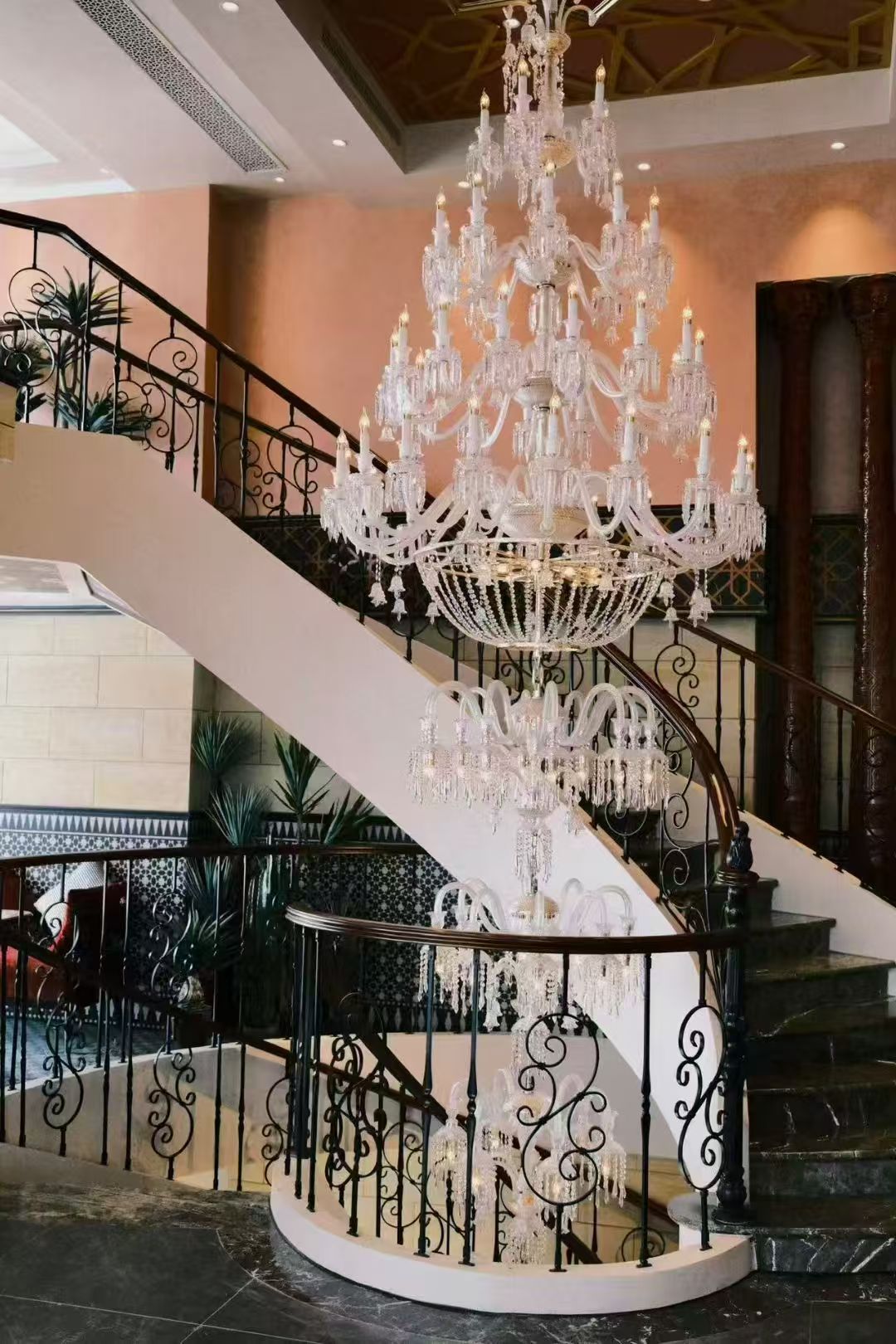 Uma escadaria imponente com um lustre branco grande e ornamentado no topo.