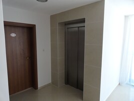 Corredor com porta de madeira e elevador moderno.