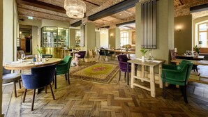 Um restaurante com soalho de madeira em padrão herringbone, mesas e cadeiras de madeira.