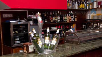 Uma área de bar com diversas garrafas de bebidas, um resfriador de vinhos e uma máquina de café.