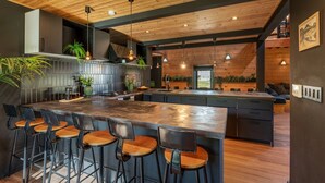 Cozinha moderna com uma ilha grande, banquetas e teto de madeira.