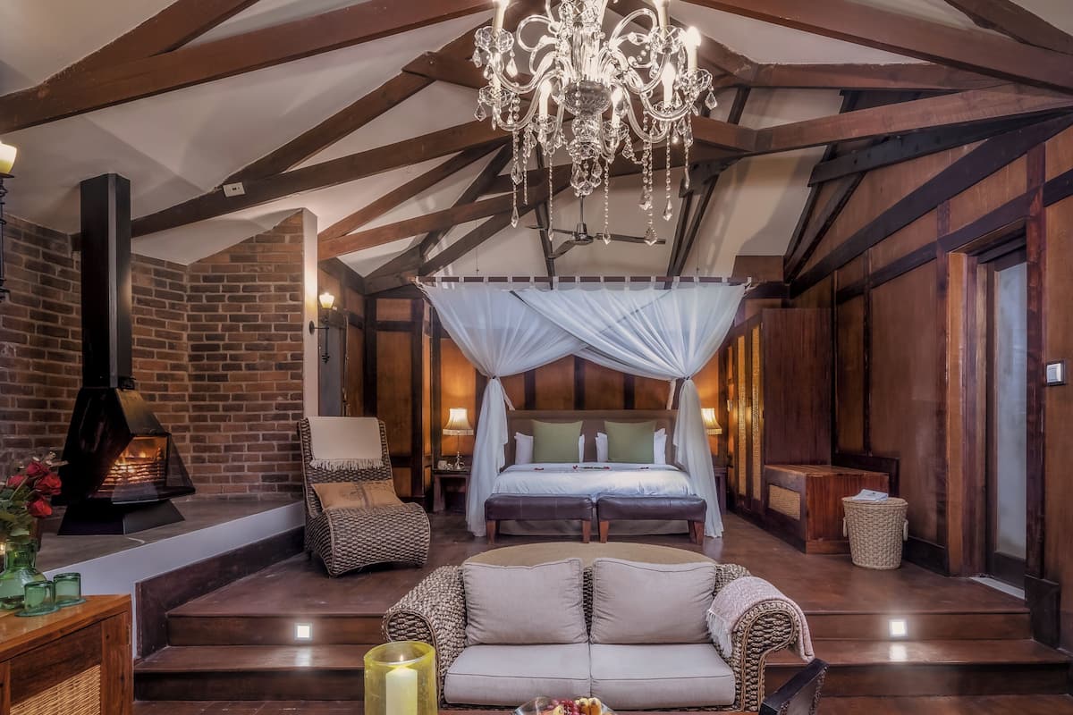 Um quarto aconchegante com cama, sofá, mesa de centro e lustre.