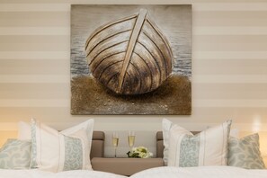 Quarto com uma cama grande, duas mesas de cabeceira e um quadro de barco na parede.