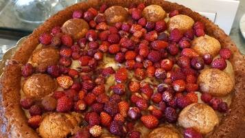 Bolo redondo com morangos e creme em uma vitrine de vidro.