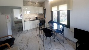 Uma cozinha moderna com armários brancos, piso de mármore e um espaço de refeições com mesa e cadeiras.