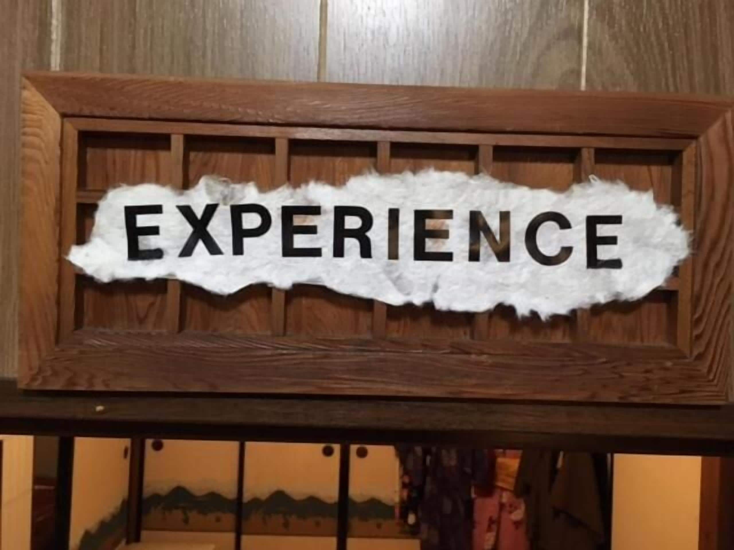 Moldura de madeira com a palavra 'EXPERIENCE' sobre fundo branco.