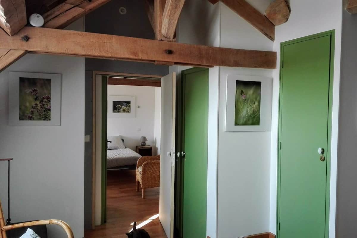 Quarto com cama, porta verde e quadro pendurado na parede.