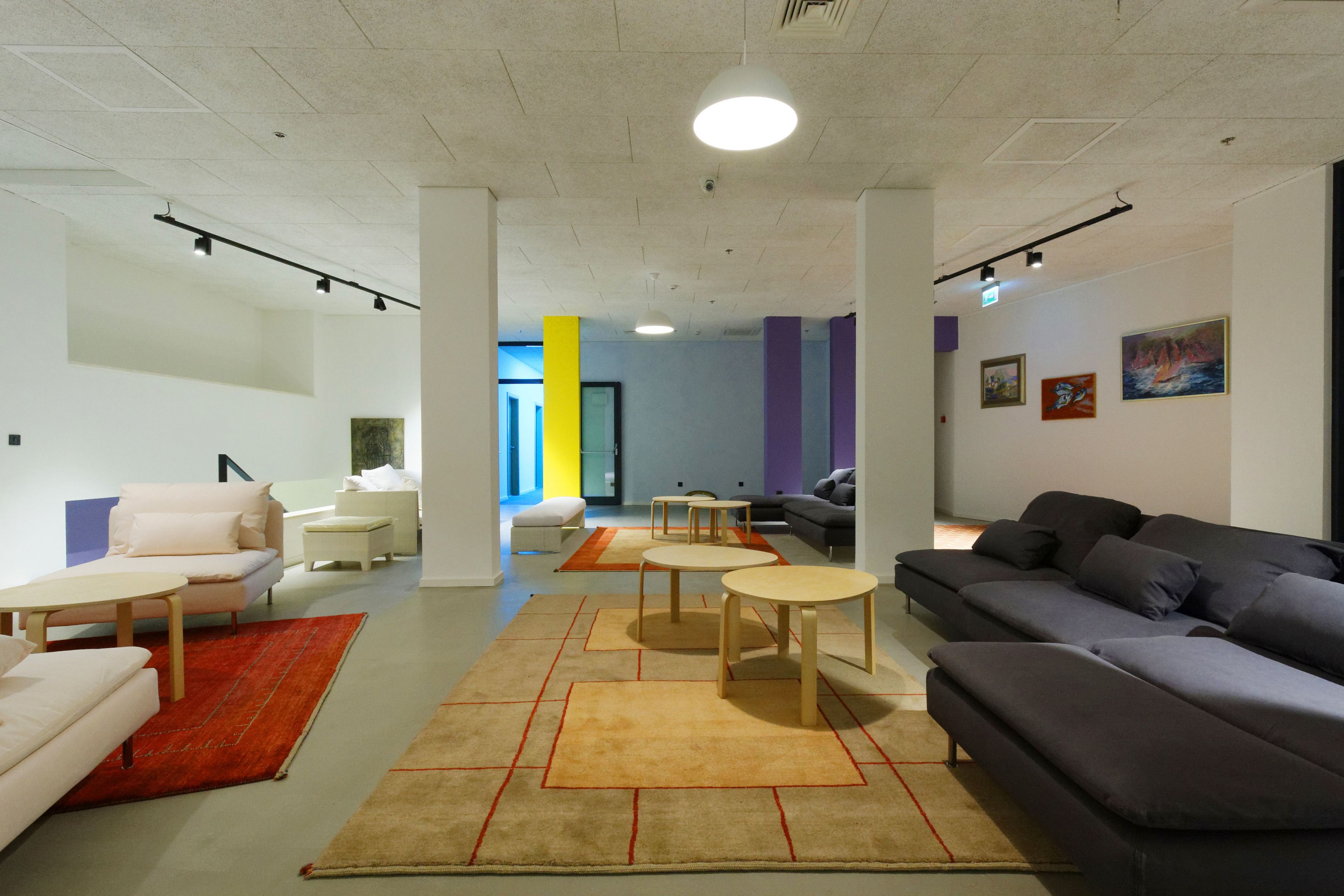 Um interior moderno com um sofá modular, uma mesinha redonda e um tapete vermelho.