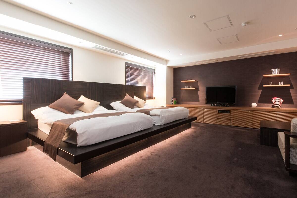 Quarto de hotel moderno com cama grande, televisão de tela plana, escrivaninha e prateleiras embutidas.