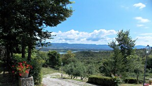 Um caminho de pedra leva a um mirante com vista para montanhas distantes e um lago.