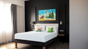Quarto de hotel moderno com uma cama grande, duas luminárias de cabeceira, um quadro pendurado e vista para o exterior.