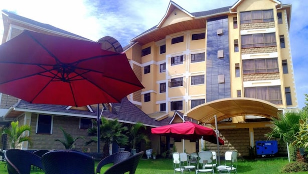 Um hotel com vários andares, mesas externas e guarda-sóis.