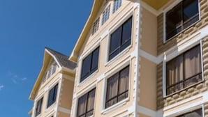 Um hotel de vários andares com fachada simétrica, janelas amplas e um pátio pavimentado.