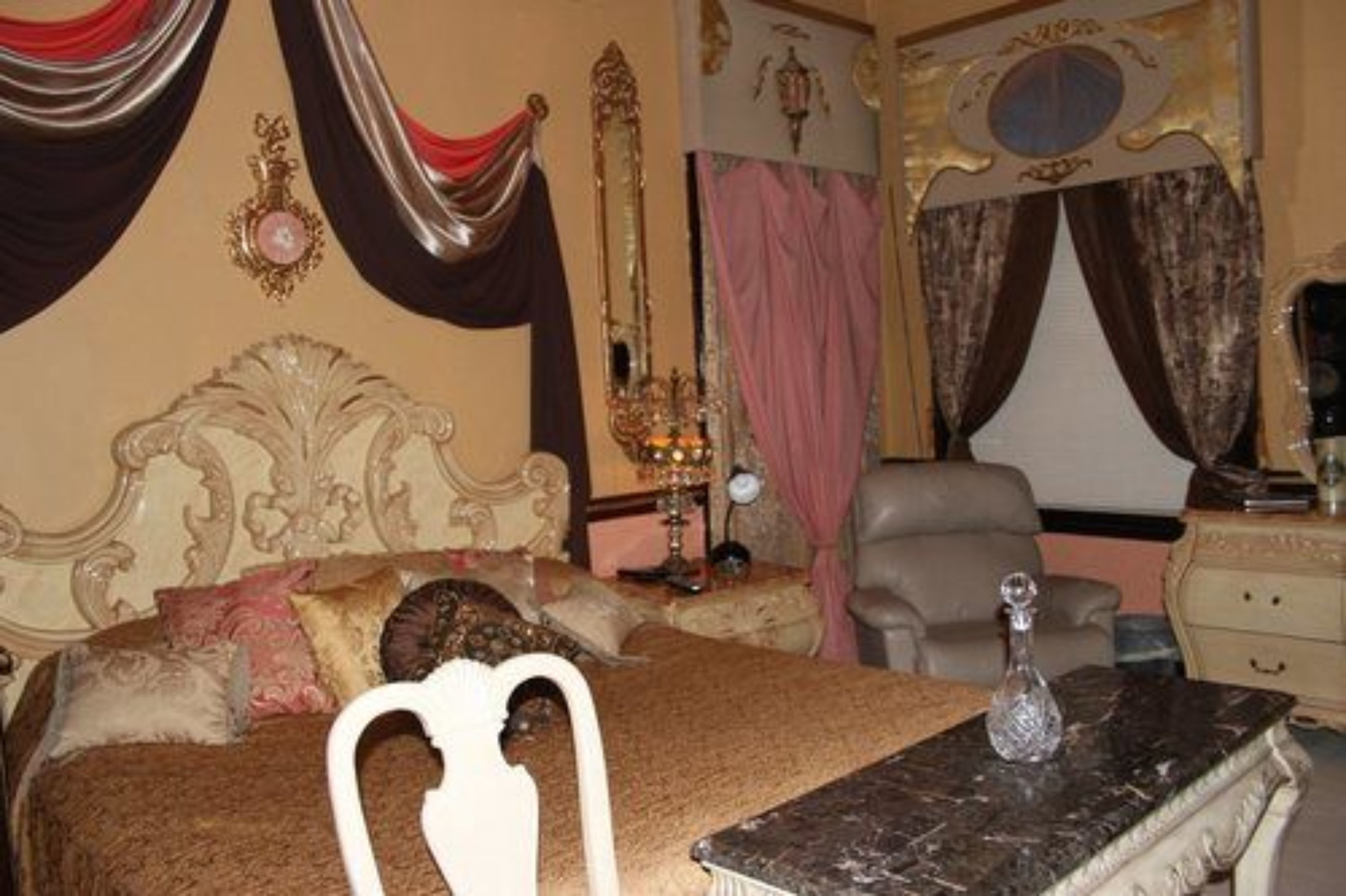 Quarto com uma cama grande, uma mesa de mármore e um candelabro.
