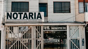 Um edifício com uma placa indicando 'Hs Pachacuteq Inn' e 'Notaria' no andar térreo.