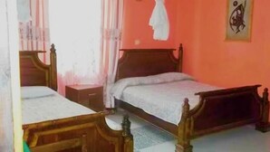 Quarto com duas camas de madeira, uma mesa de cabeceira e uma parede com um objeto decorativo.
