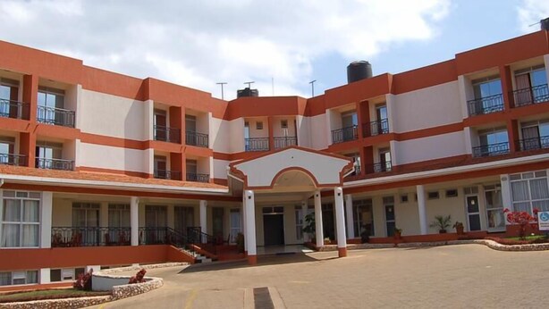 Hotel com vários andares, entrada central, varandas em cada andar e um pátio.