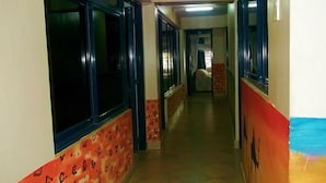 Um corredor com piso de azulejos, parede de tijolos e uma janela à esquerda.