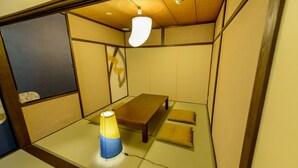 Um quarto japonês tradicional com piso de tatame, uma mesa de madeira baixa e um moderno aparelho de iluminação.