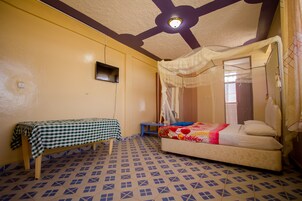 Quarto com cama, mesa e ventoinha no teto.