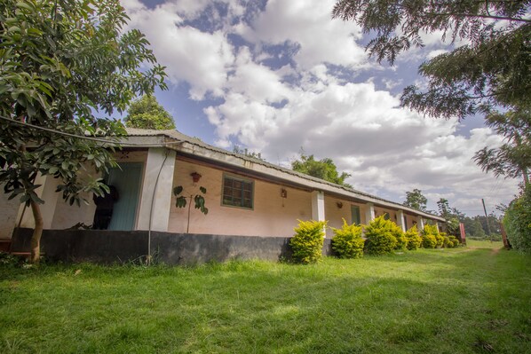 Um edifício térreo com telhado plano, varanda frontal e gramado bem cuidado.