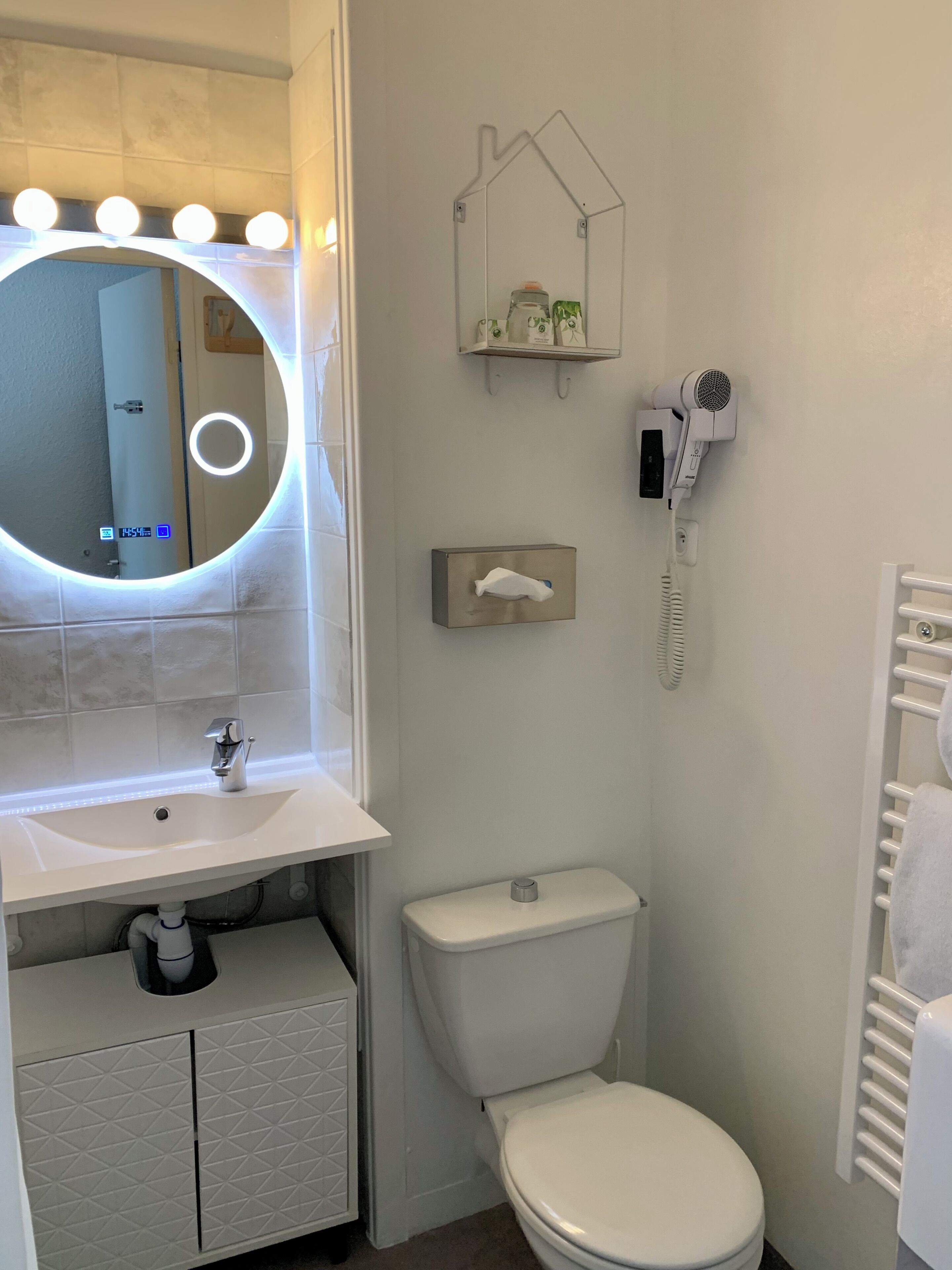 Casa de banho com lavatório, sanita, secador de cabelo e barra para toalhas.