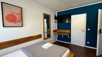 Um quarto moderno com uma cama, um banquinho, um espelho e uma porta.