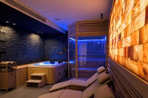 Um spa moderno com sauna de madeira, banheira de hidromassagem e área de relaxamento com bancos.