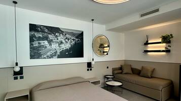 Quarto moderno com uma cama grande, um sofá, um espelho redondo e um quadro pendurado na parede.