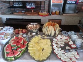 Buffet com diversos alimentos, incluindo melancia, abacaxi e tomates fatiados.