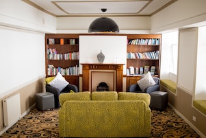 Uma sala de estar com lareira, dois sofás, uma mesa de centro e duas estantes repletas de livros.