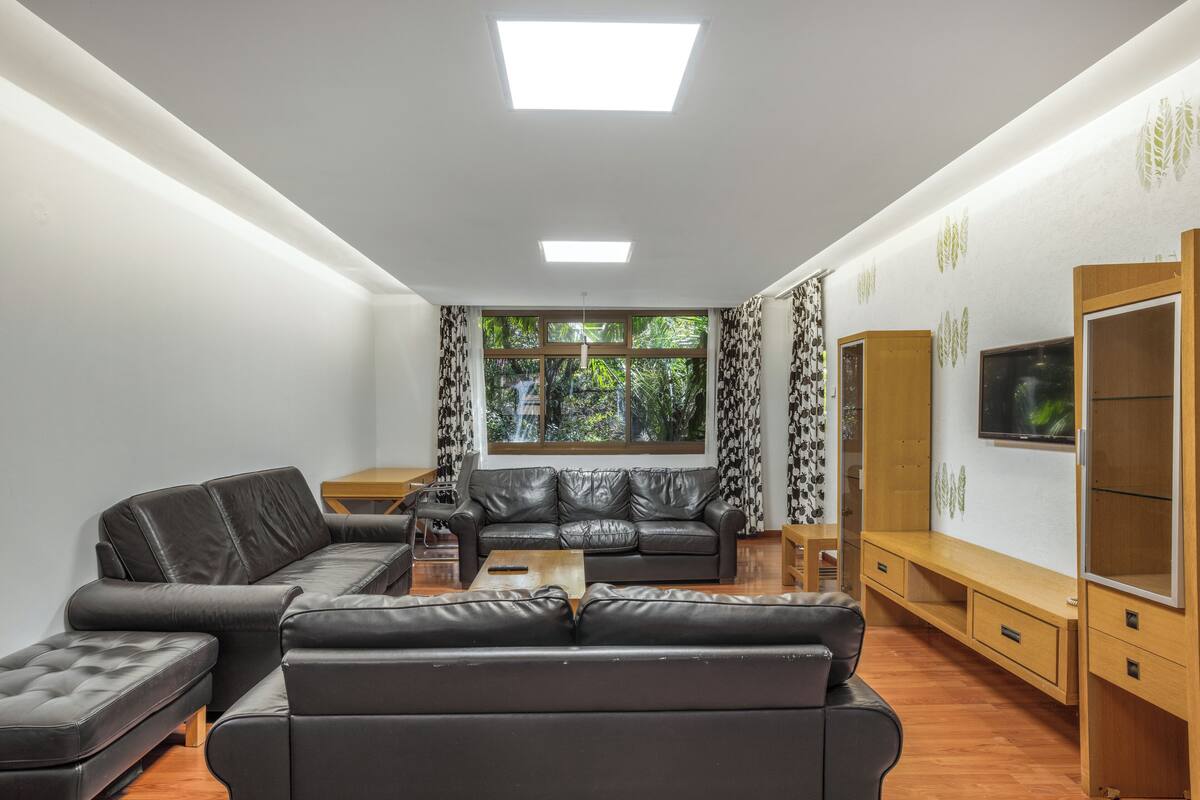 Uma sala de estar moderna com um sofá modular, uma mesa de centro e uma TV sobre um suporte de madeira.