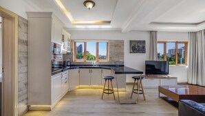 Uma cozinha moderna com uma ilha grande, banquetas e uma televisão de tela plana.