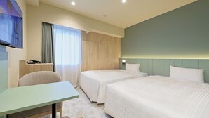 Quarto de hotel com duas camas, uma mesa, uma cadeira, uma televisão e uma janela com cortinas.