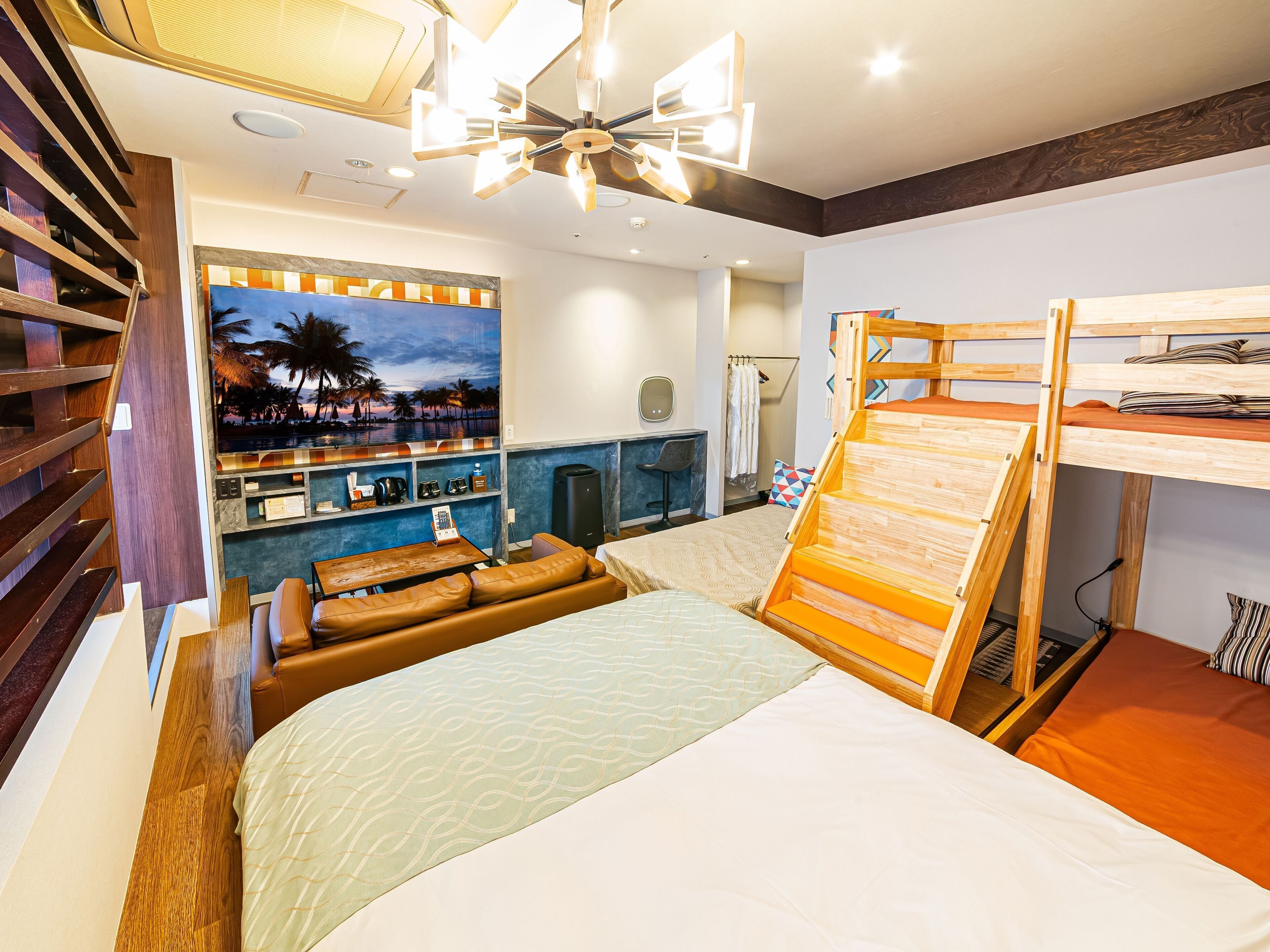 Quarto de hotel moderno com cama, escrivaninha, área de estar e beliche.