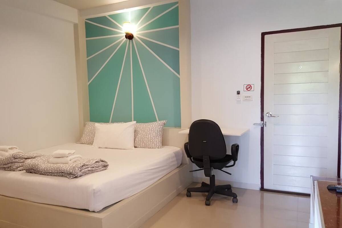 Quarto com cama, escrivaninha e porta.