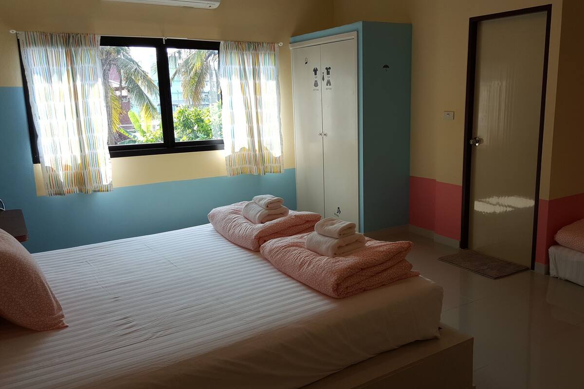 Quarto com cama, duas mesas de cabeceira, um guarda-roupa e uma porta.