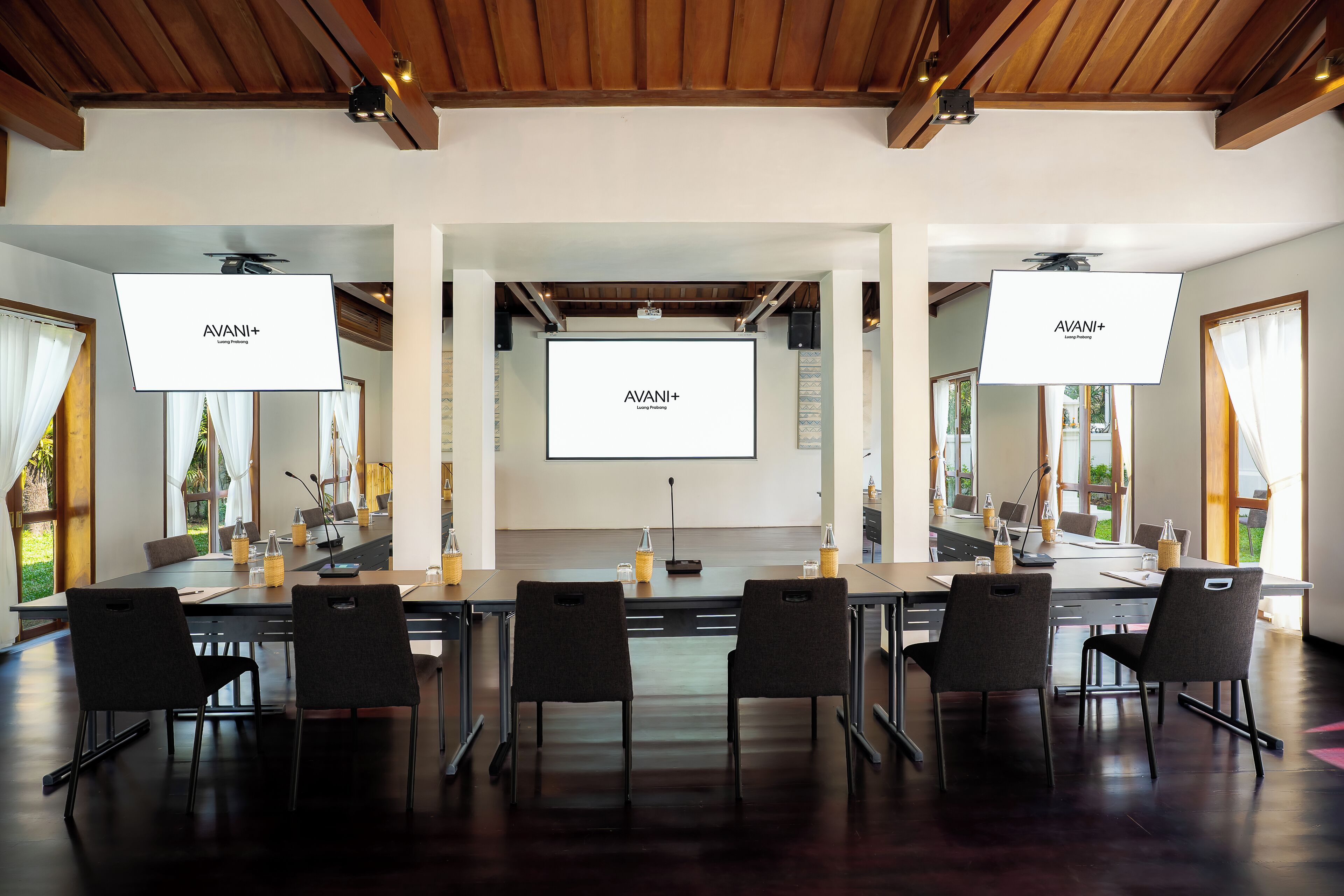 Uma sala de conferências com uma mesa comprida, seis cadeiras e duas telas AVANTI+ nas paredes.