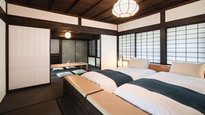 Um quarto tradicional em estilo japonês, com piso de tatame, cama de madeira baixa, porta de tela deslizante shoji e um lanterna de papel pendurada.